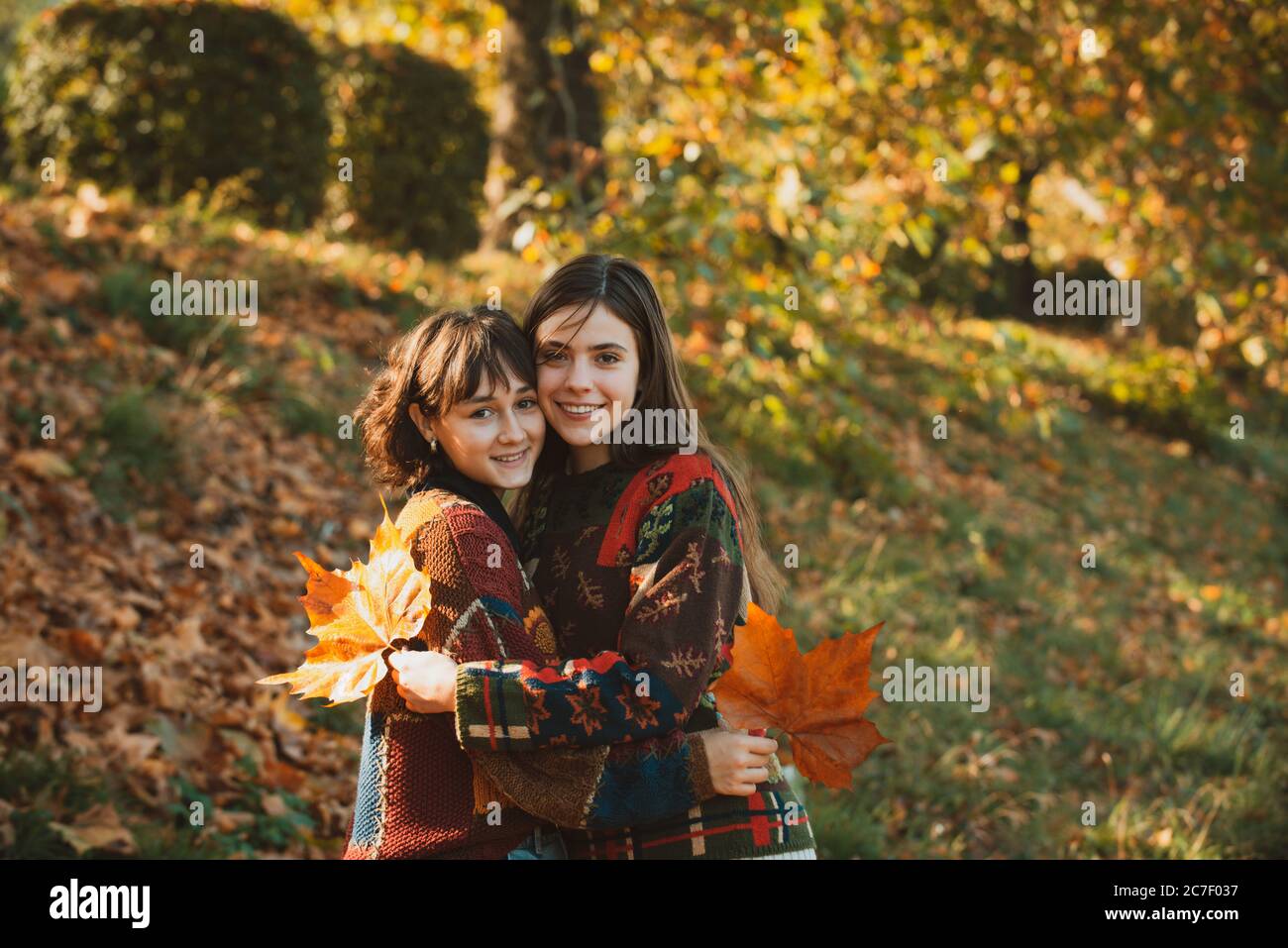 Two girls with bouquets of autumn leaves. Cute young students stand in ...