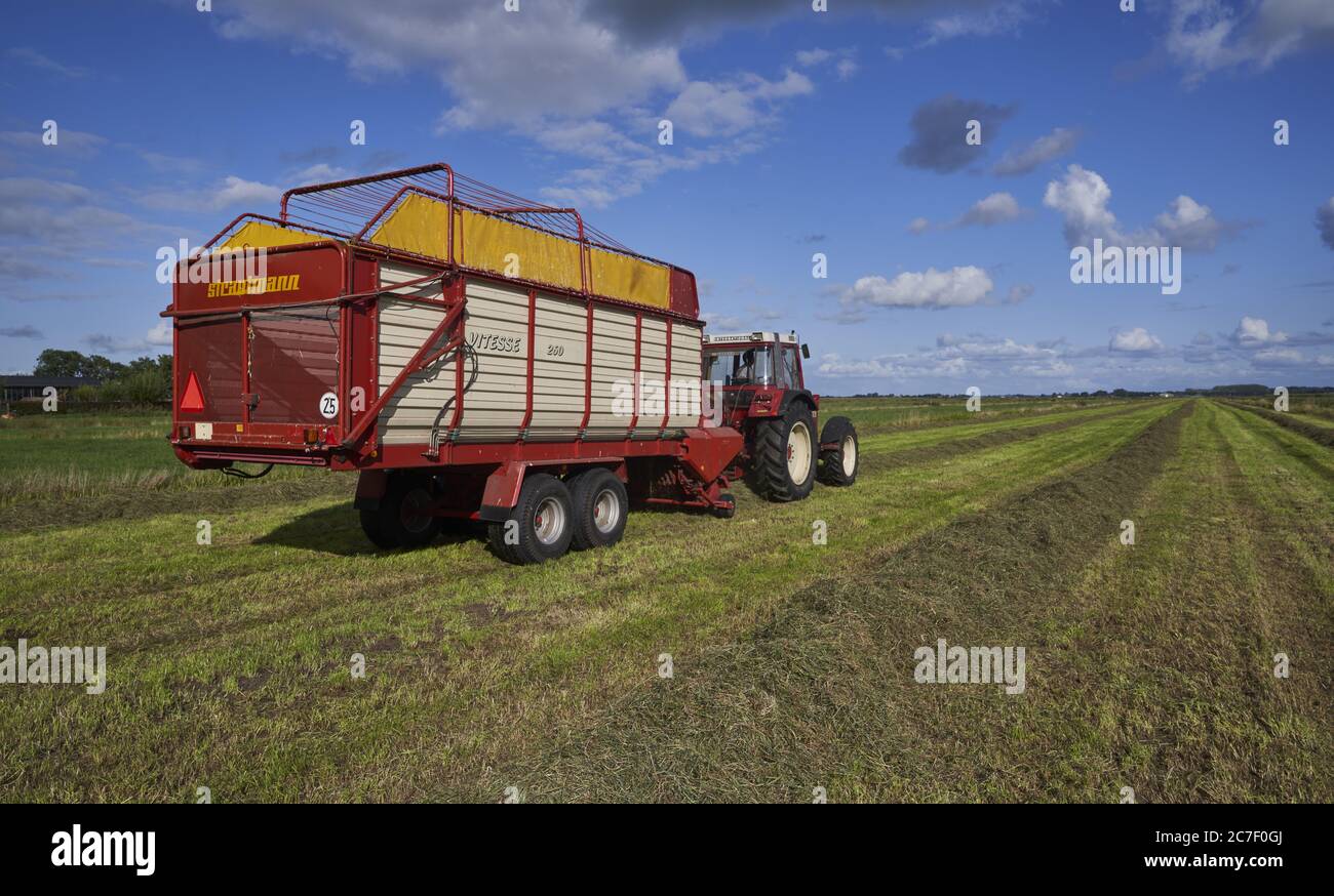 Red tractor driving on a farm field under a blue sky at daytime Stock ...
