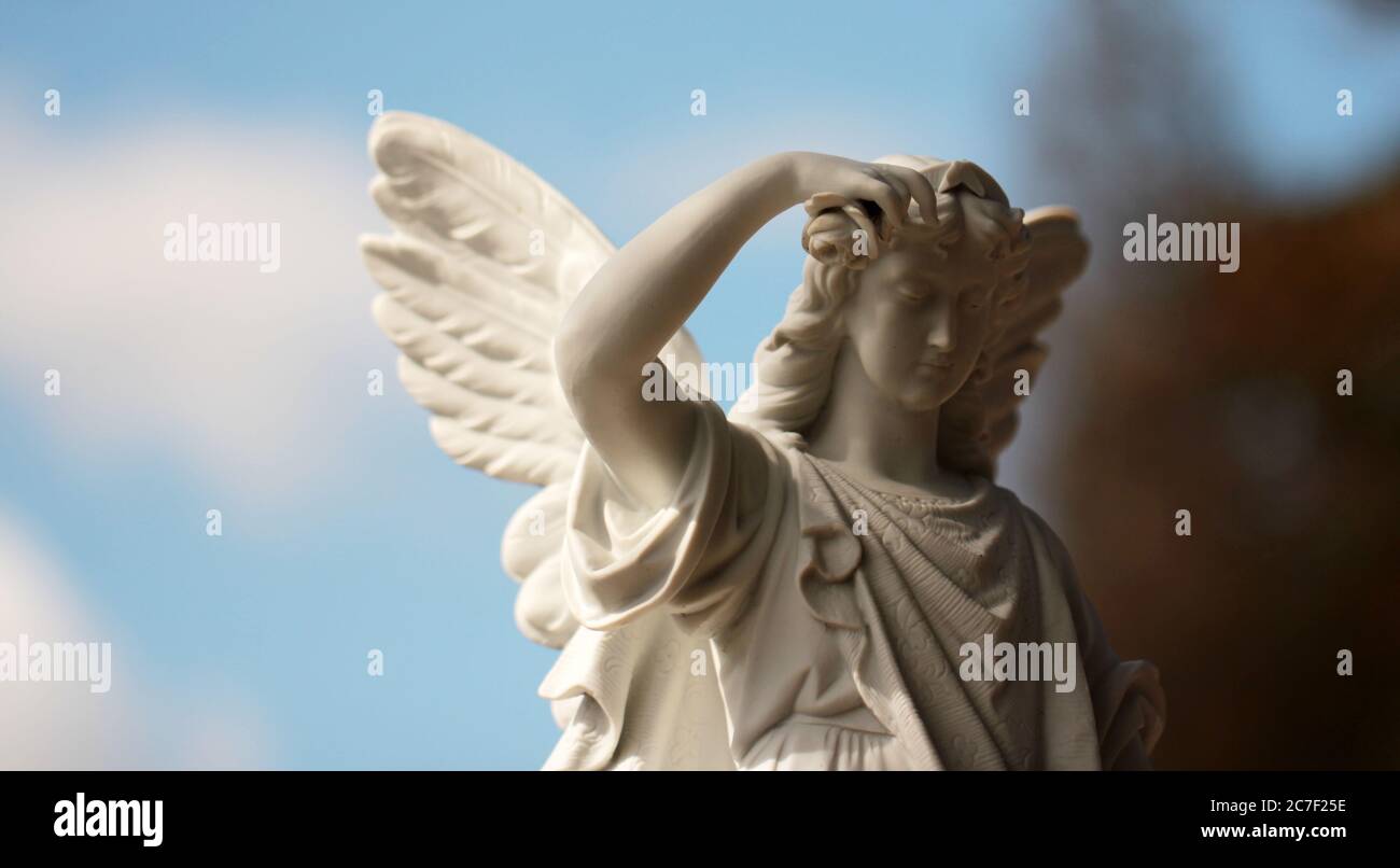 Horizontal shot of an angel statue in a cemetery weathered by time but ...