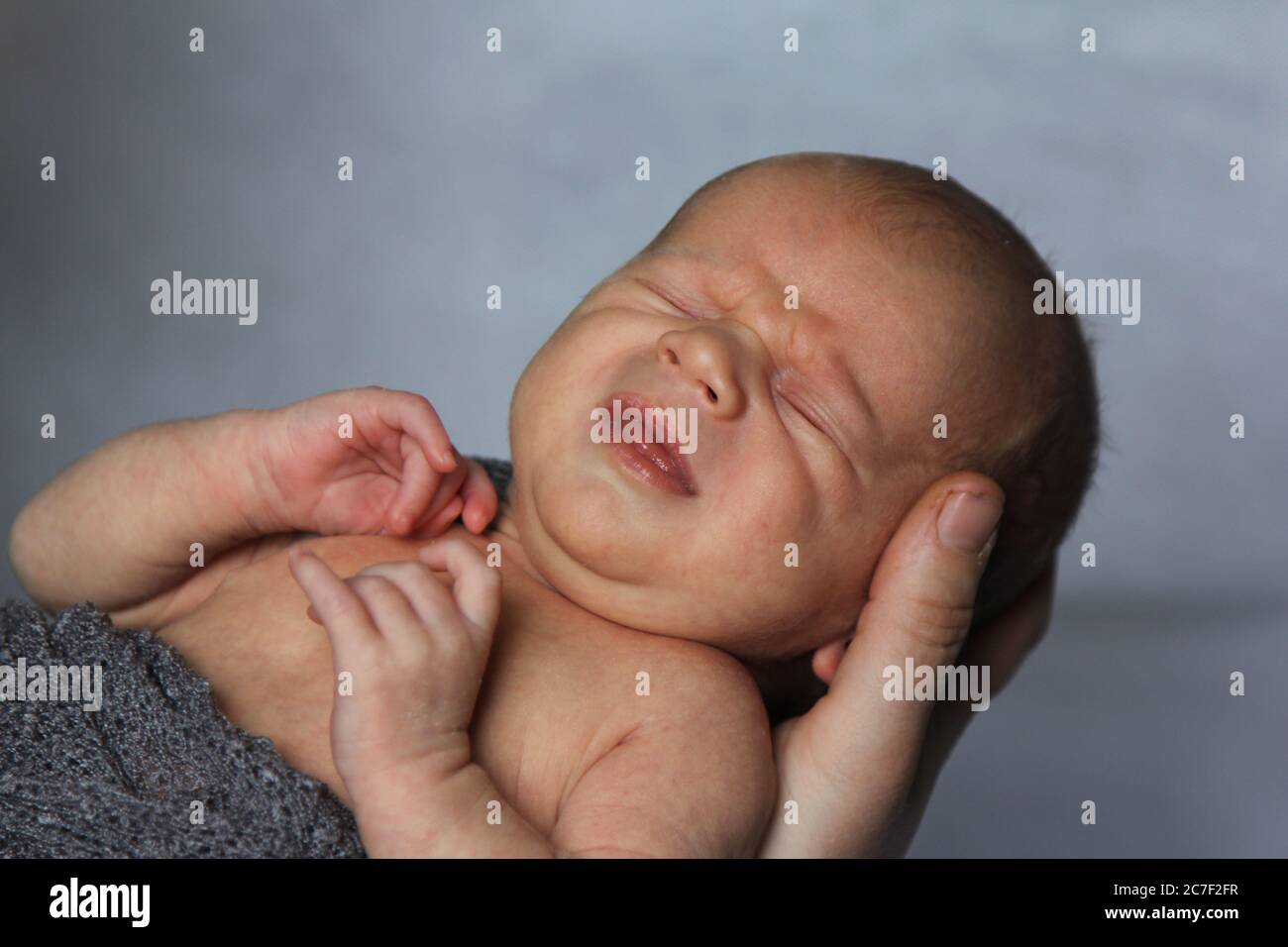AUCKLAND, NEW ZEALAND - Aug 27, 2017: Newborn baby grimaces in pain or ...
