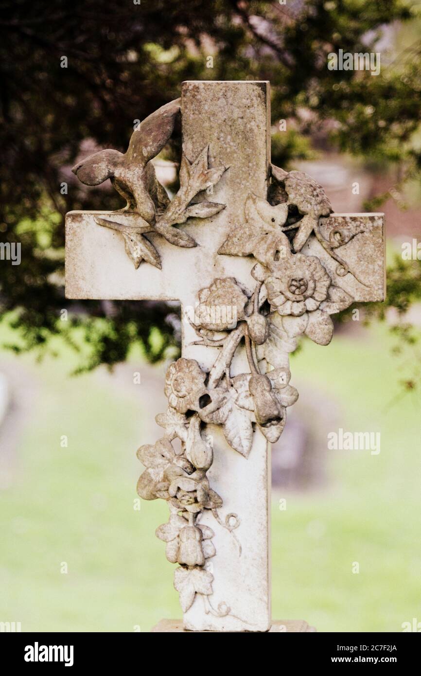Vertical shot of a beige and white floral concrete cross with a blurred ...