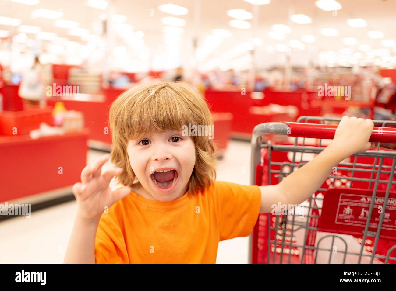 Funny boy with shopping cart full of fresh organic vegetables and ...