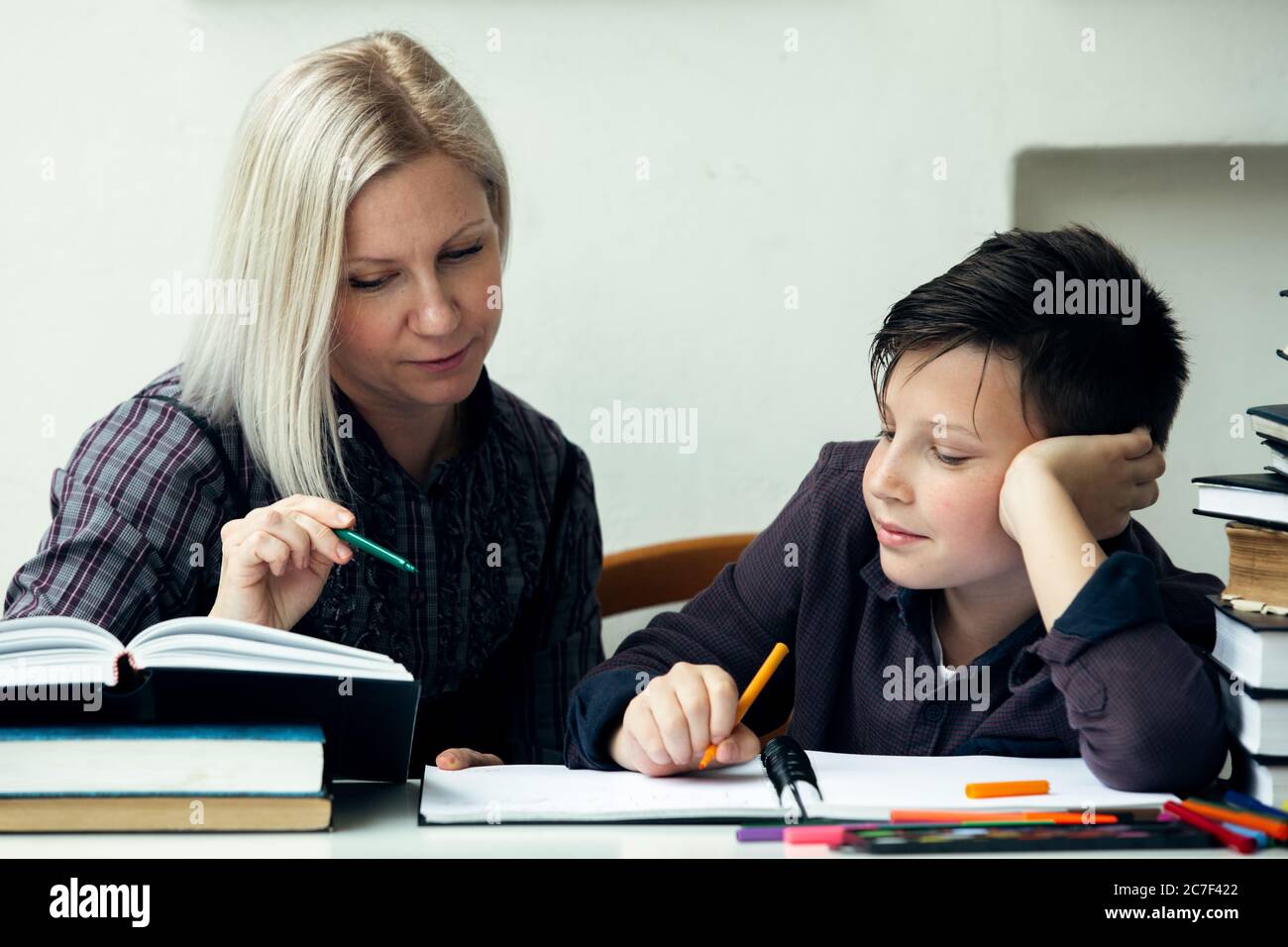 Schoolboy and tutor sits at a table does homework Stock Photo - Alamy
