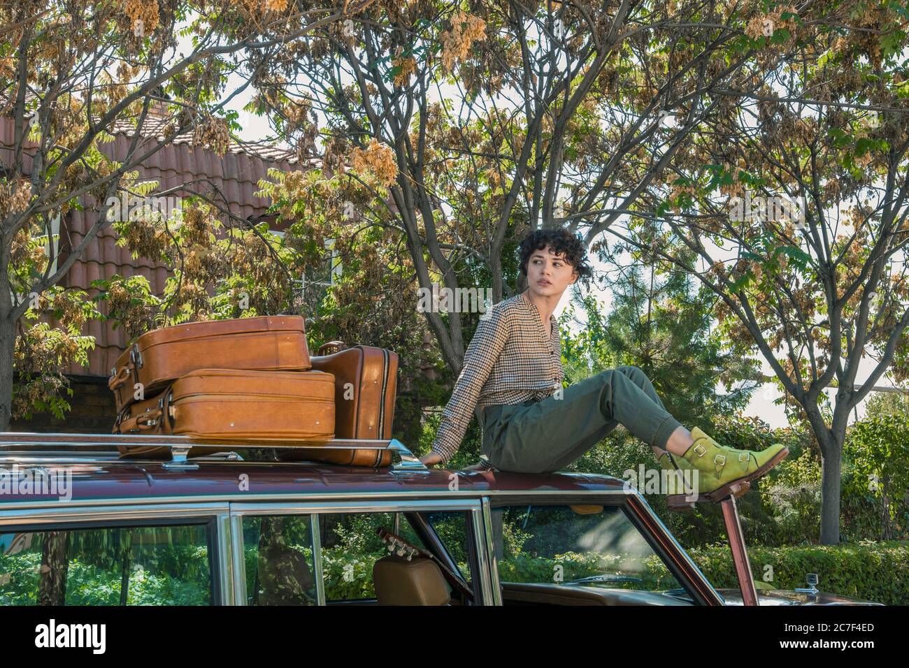 Female model sitting on a car posing for a photoshoot with suticases to ...