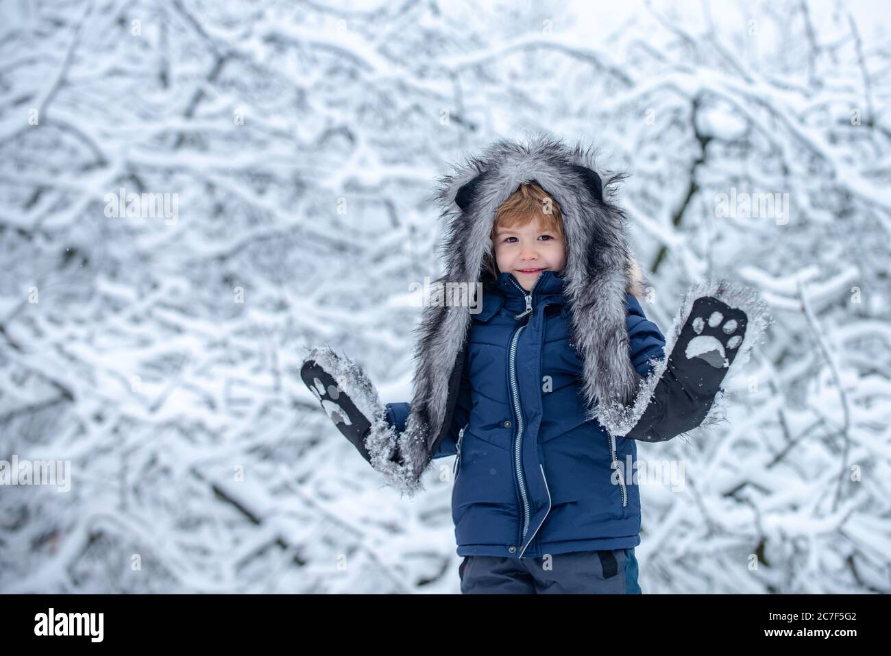 Little child in snow field. Funny kid coming to the winter forest on ...