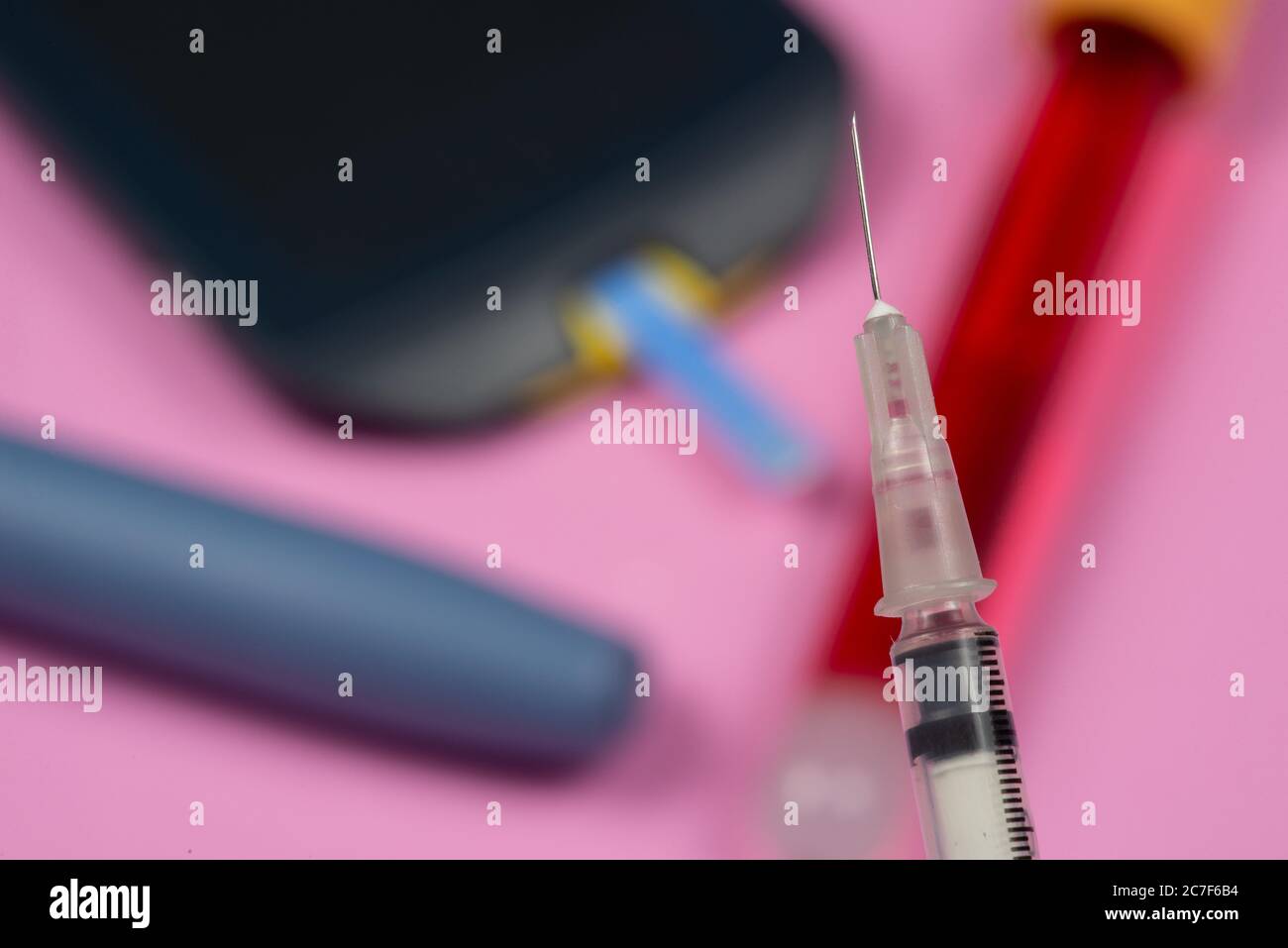 insulin syringe in the foreground, with blurred diabetes objects in the ...