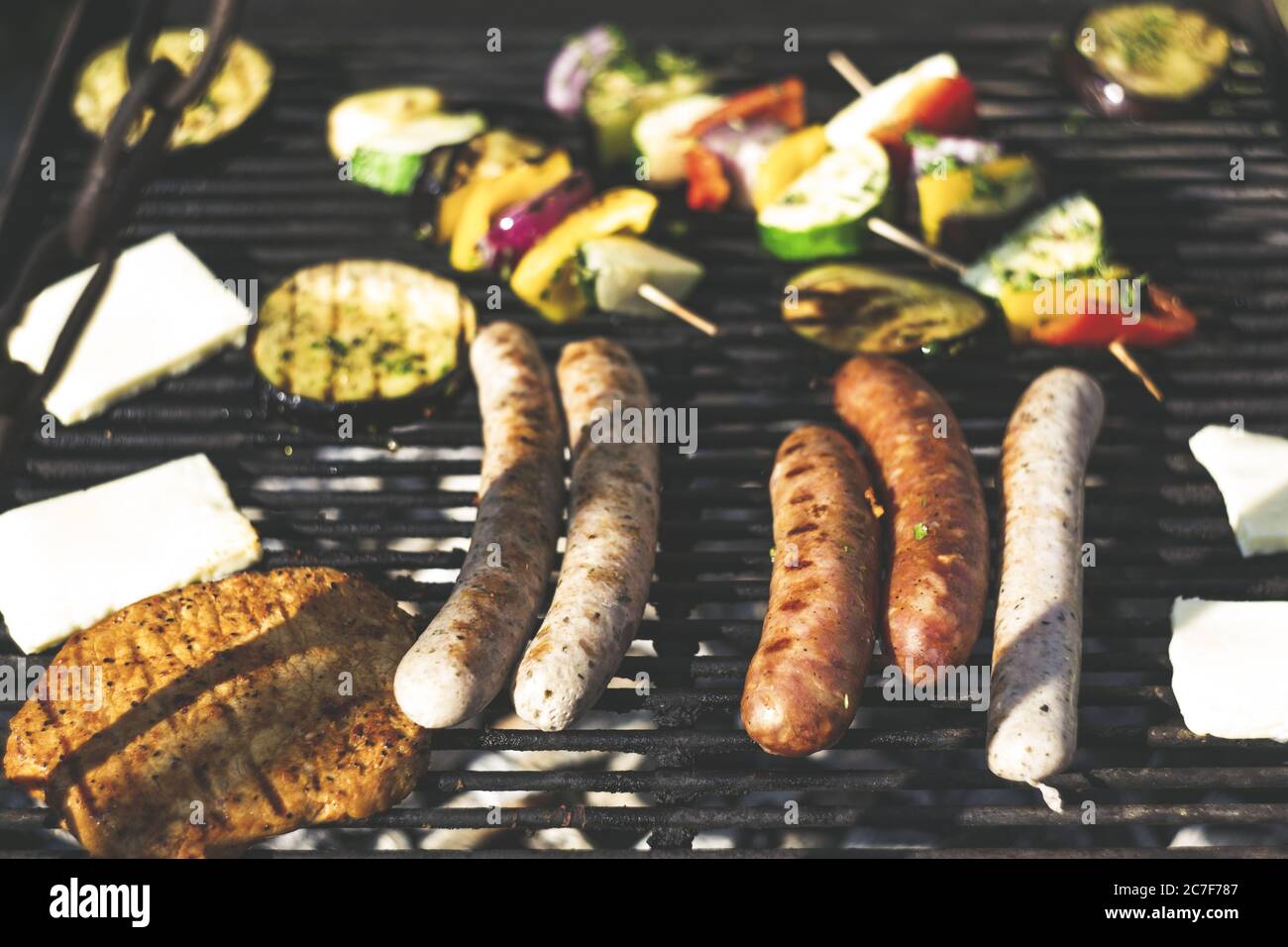 Closeup shot of sausages and vegetables being cooked on a barbecue ...
