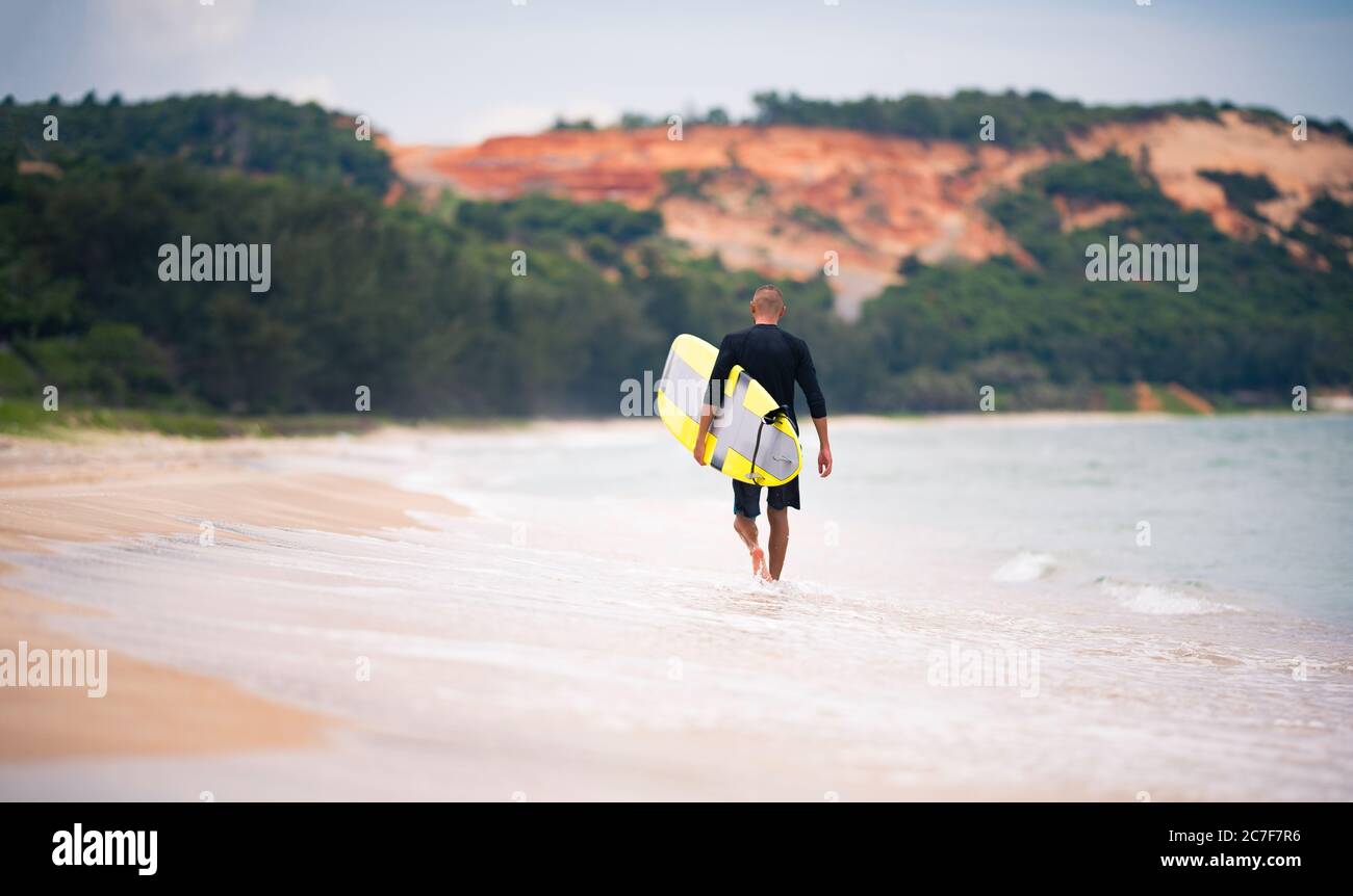 Tired surfer going away with yellow surfboard. Summer vacation holiday ...
