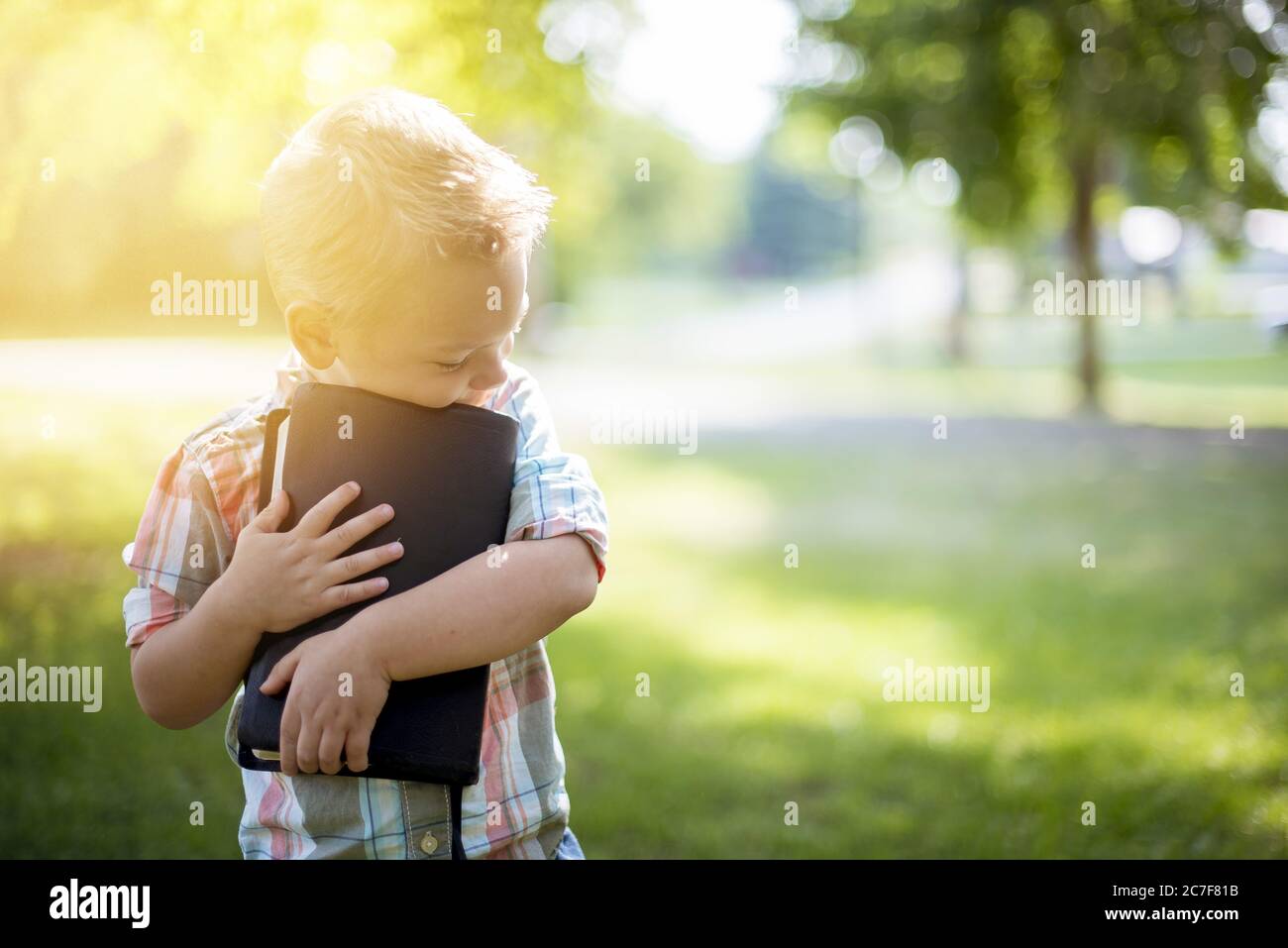 Closeup shot of a child holding the bible against his chest with a ...