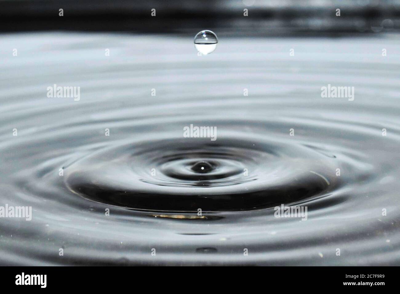 Amazing shot of a water drop falling on a water surface and making a ...