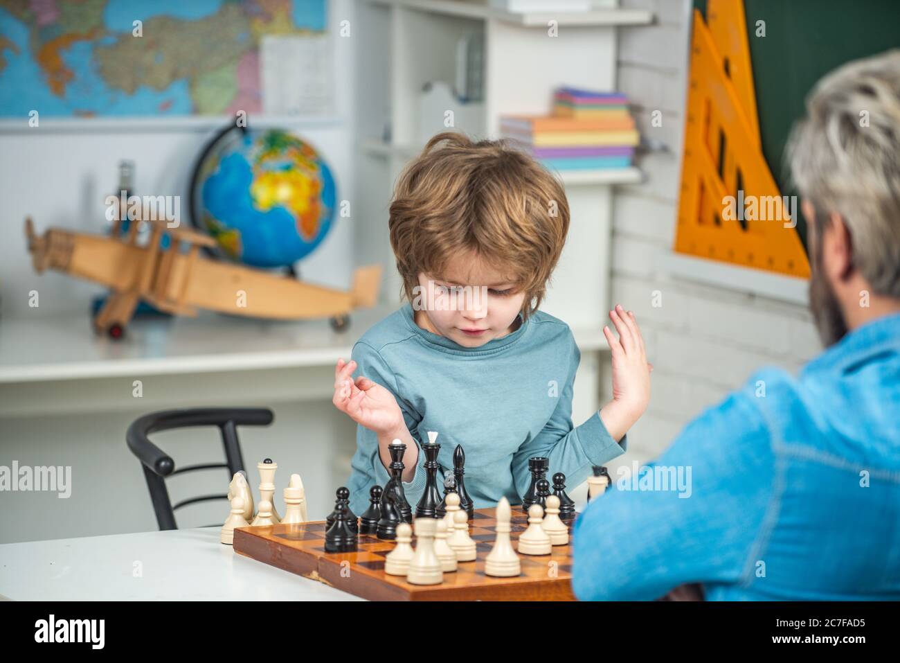 Concentrated boy developing chess strategy, playing board game ...