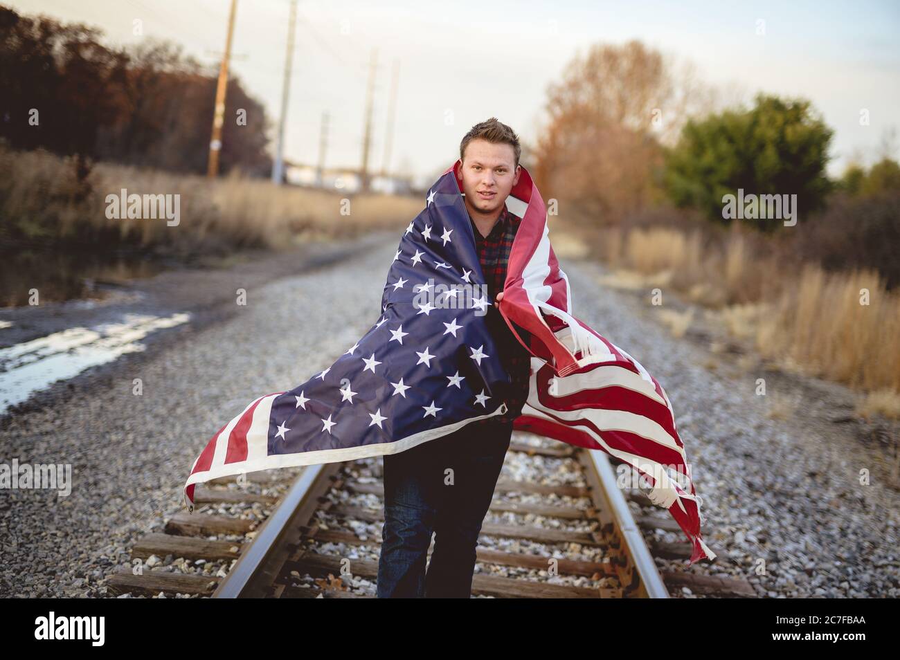 White male covered in the flag of the United Staes of America standing ...