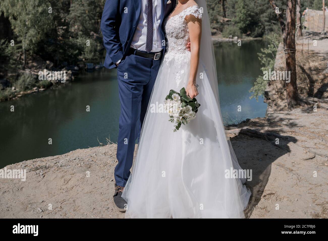 the groom with the bride on the stones near lake Stock Photo - Alamy