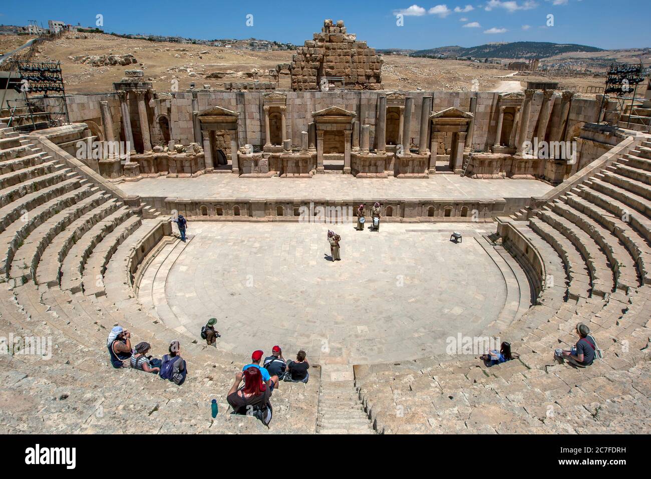 Tourists sit in the ruins of the South Theatre at the ancient city of ...