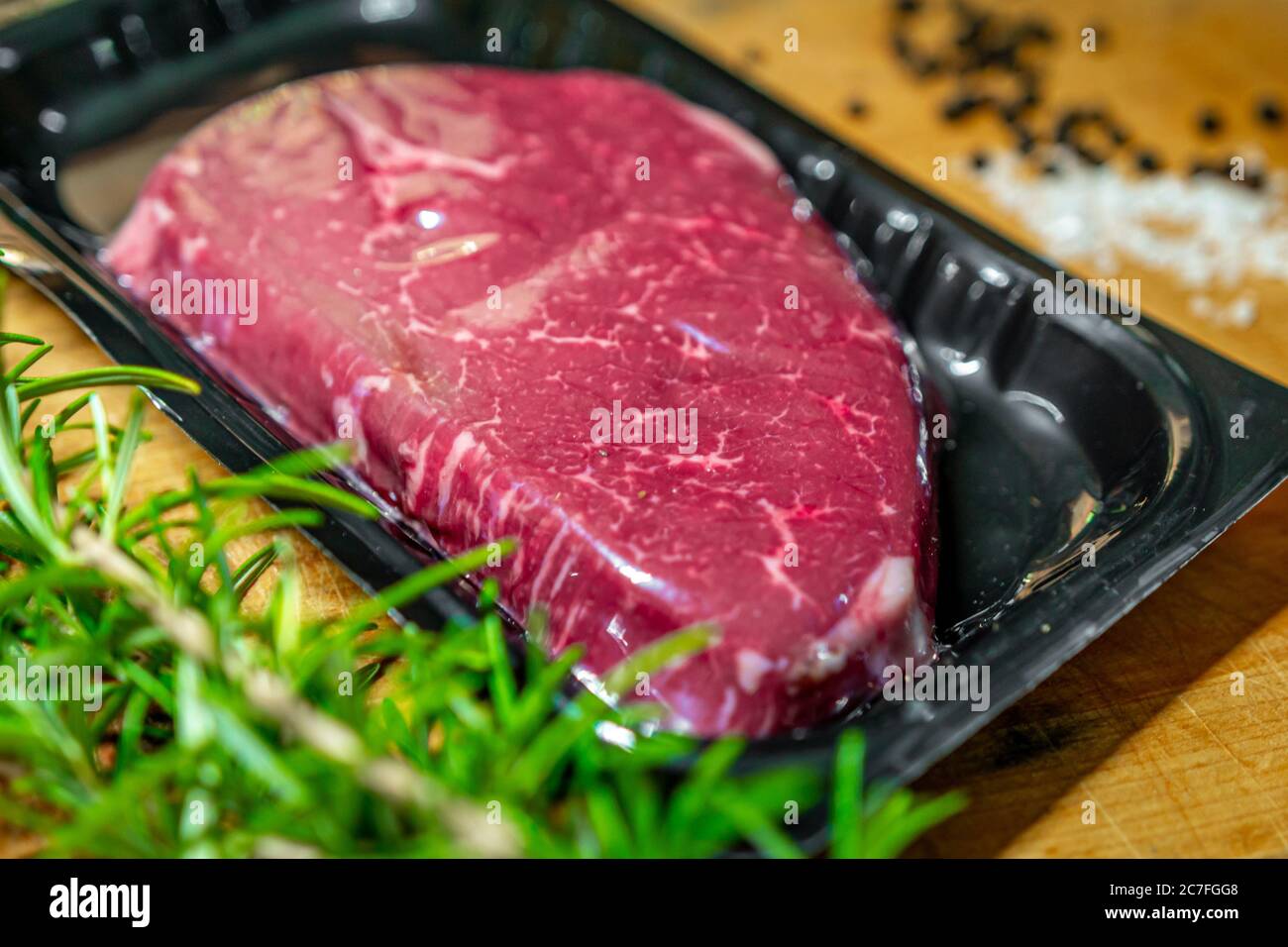 Beef steak in vacuum skin packaging and spices on wooden chopping board ...