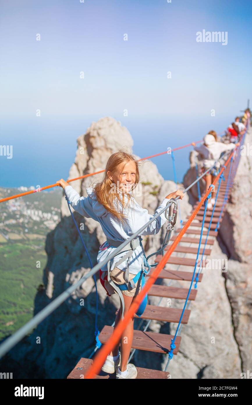 Girls crossing the chasm on the rope bridge. Black sea background ...