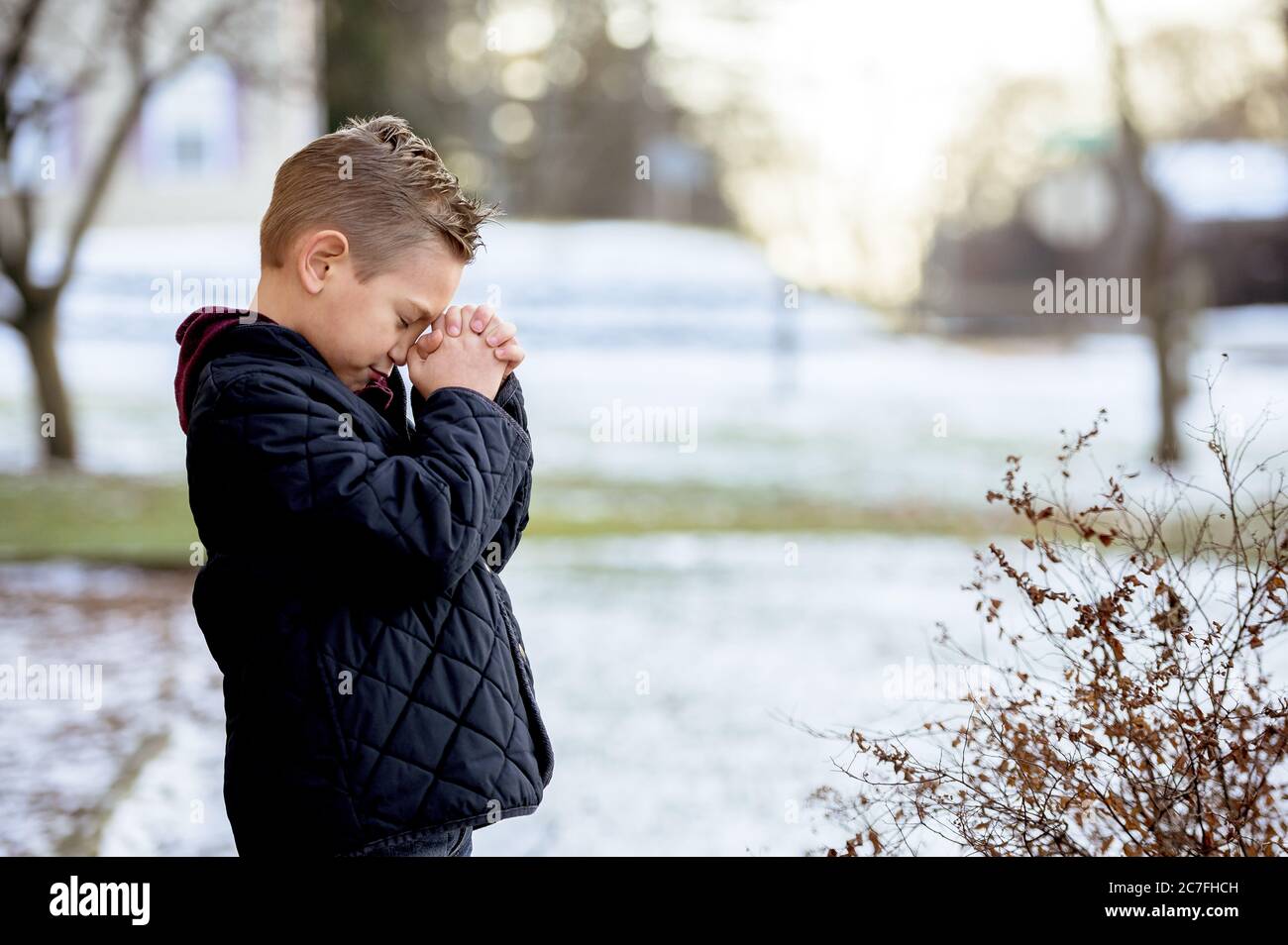 Cute little boy praying with closed eyes in the middle of the winter ...