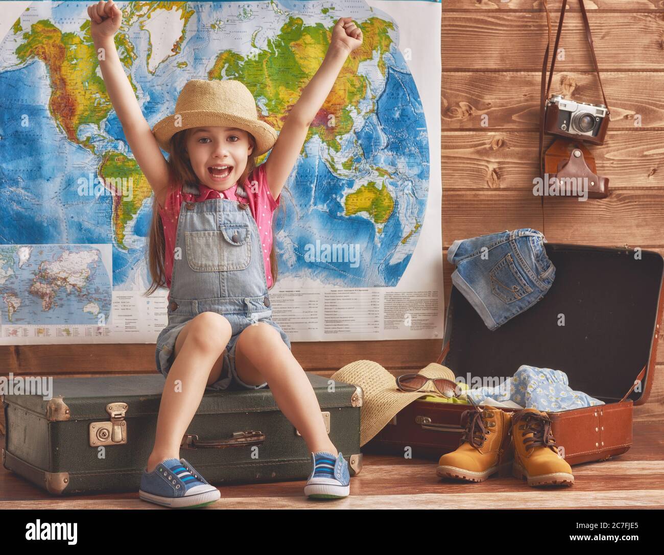 Happy child girl getting ready for the journey. Girl packs her bags and ...