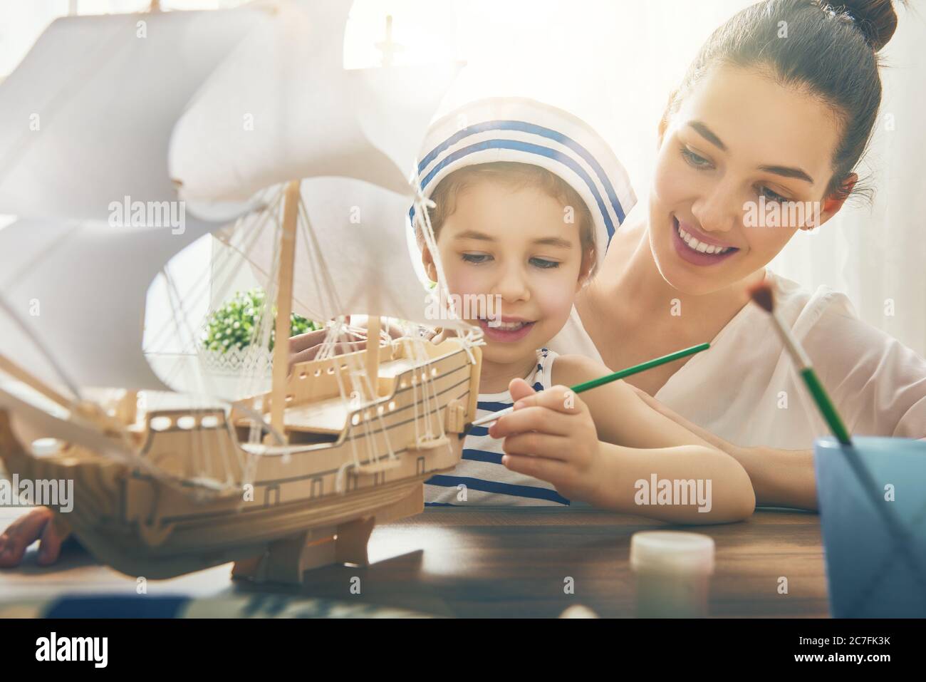 Mother and her child girl making model ship. Dreams of sea, adventures ...