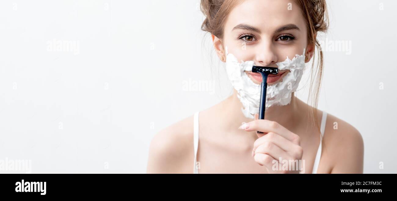 Beautiful young caucasian woman shaving her face by razor on white ...