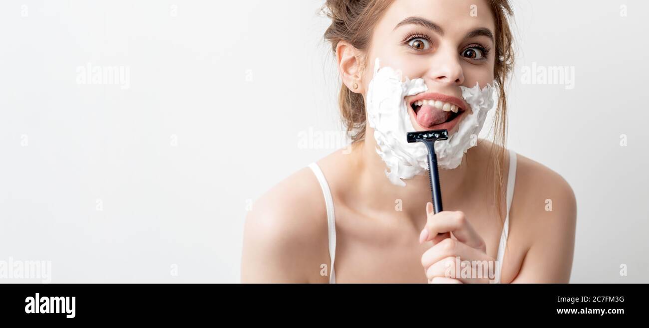Beautiful young caucasian woman shaving her face by razor on white ...
