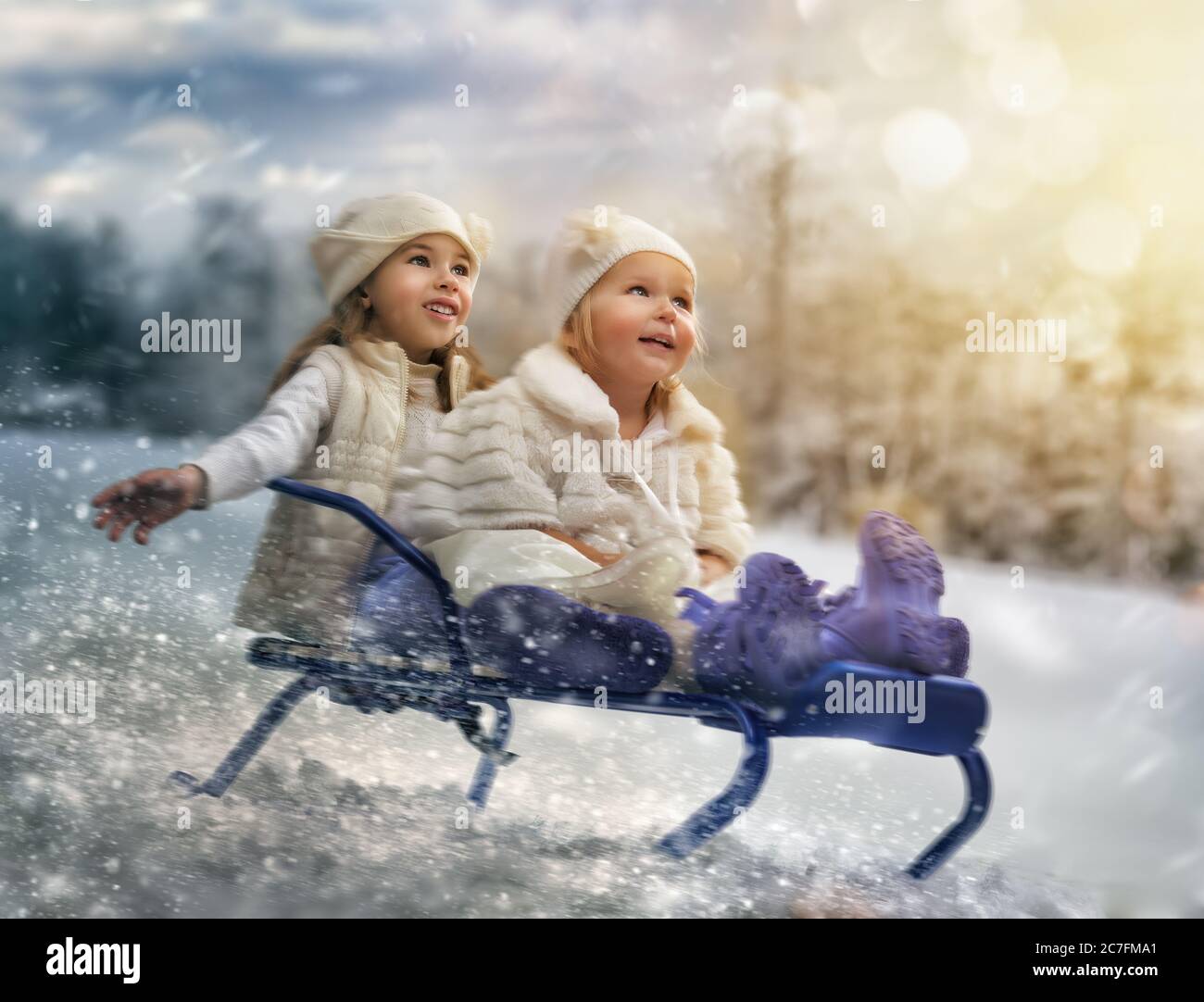 two happy girls on sled Stock Photo - Alamy