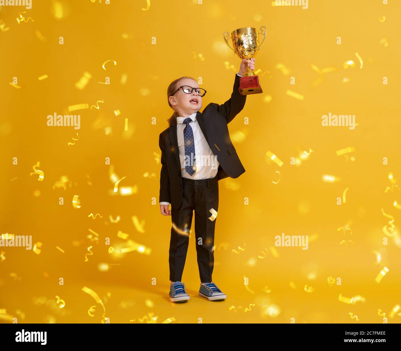 Little child is winner. Kid on the background of bright yellow wall ...