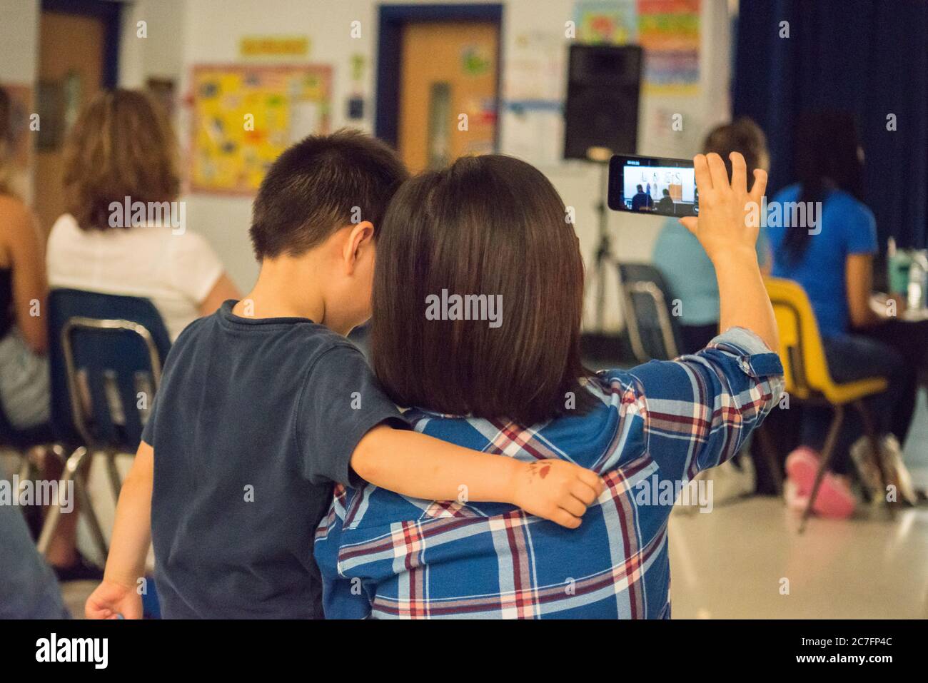 Mother and her child recording a video of someone giving a lecture ...