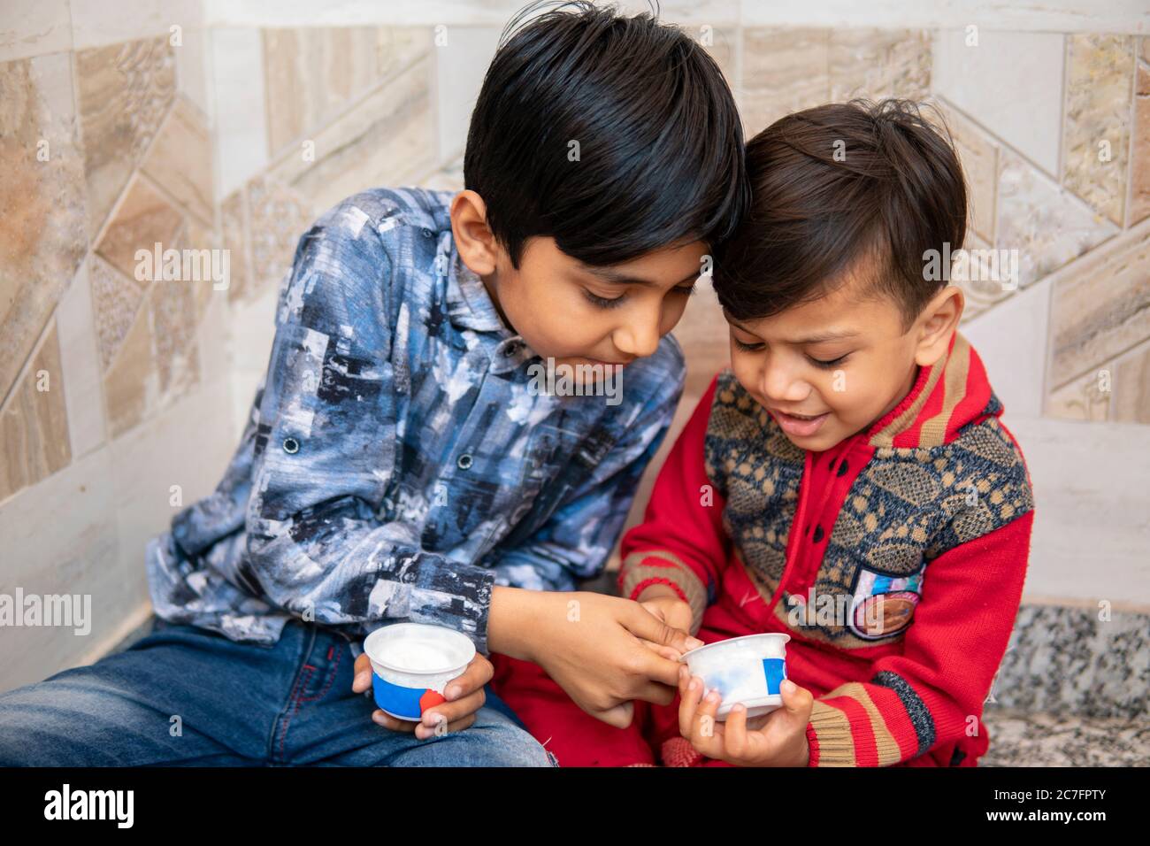 Cute little boy sharing cup ice cream with his brother Stock Photo - Alamy
