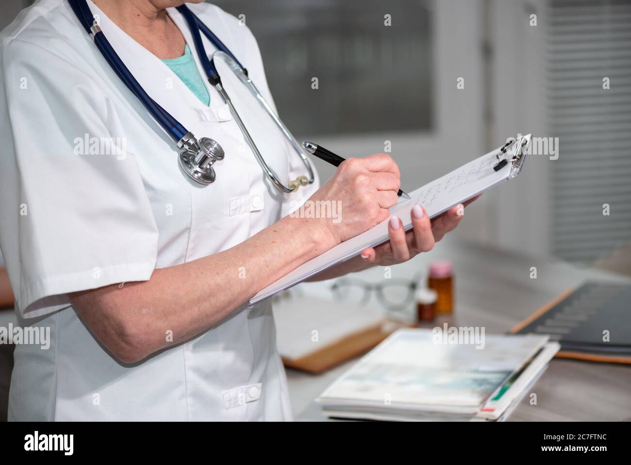 Female doctor taking notes on clipboard in medical office Stock Photo ...