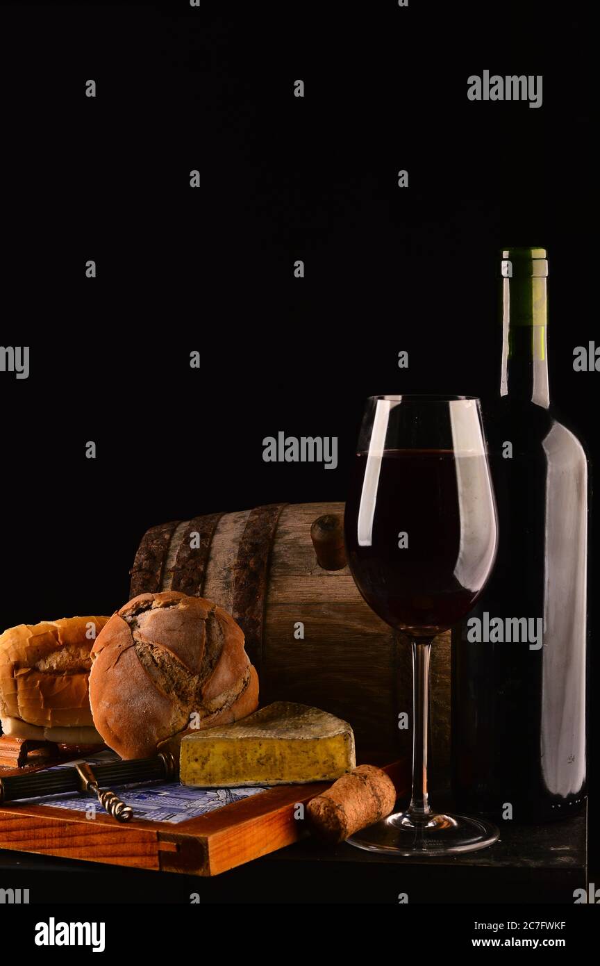 Glass of red wine and the bottle nearby, bread and barrel studio shot ...