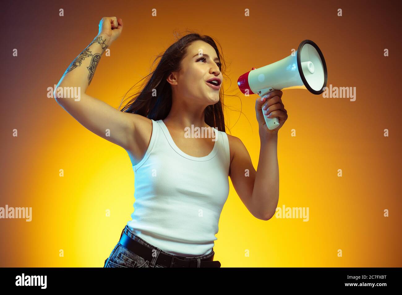 Shouting. Portrait of young caucasian woman isolated on gradient yellow ...