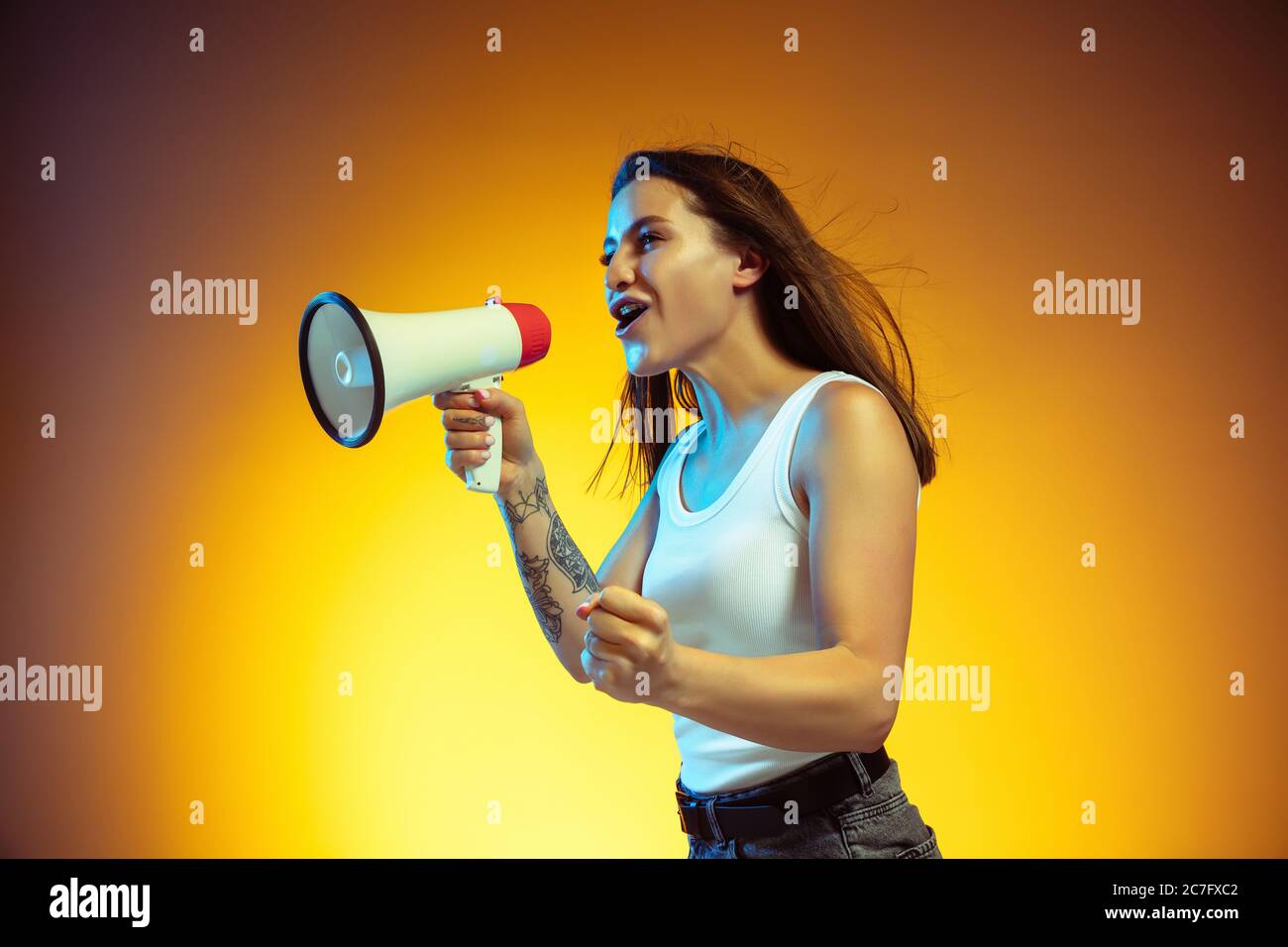 Shouting. Portrait of young caucasian woman isolated on gradient yellow ...