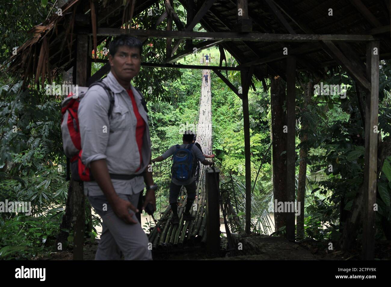 Visitors and guides crossing a river through a suspension bridge in ...