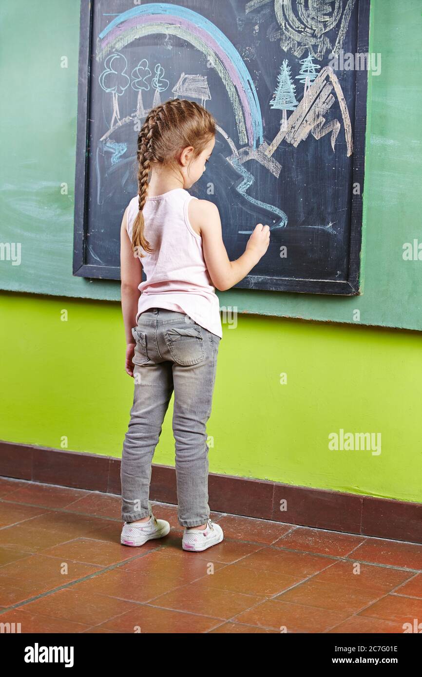 Girl in kindergarten draws on a blackboard with colorful chalk Stock ...