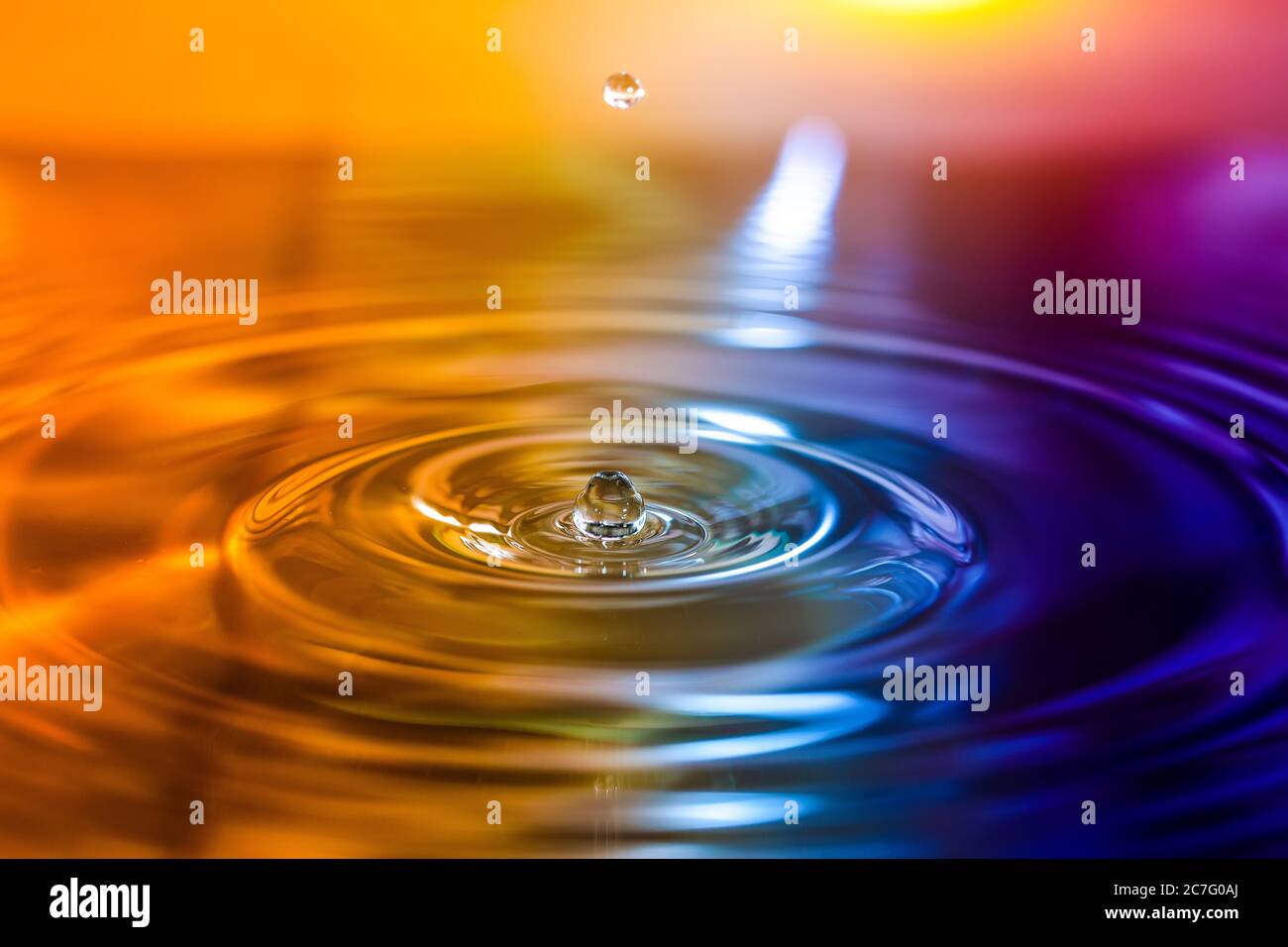 Macro photo of water drops falling into a pool of water, causing a ...