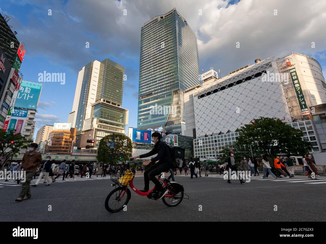 A young man delivering food with Uber Eats rides his rental bicycle ...