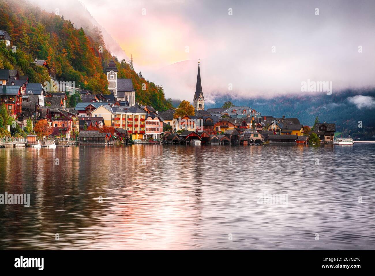 Scenic view of famous Hallstatt mountain village with Hallstatter lake. Foggy autumn sunrise on ...