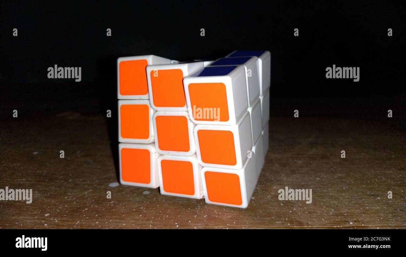 Closeup shot of a solved Rubik's Cube on a wooden surface with black ...