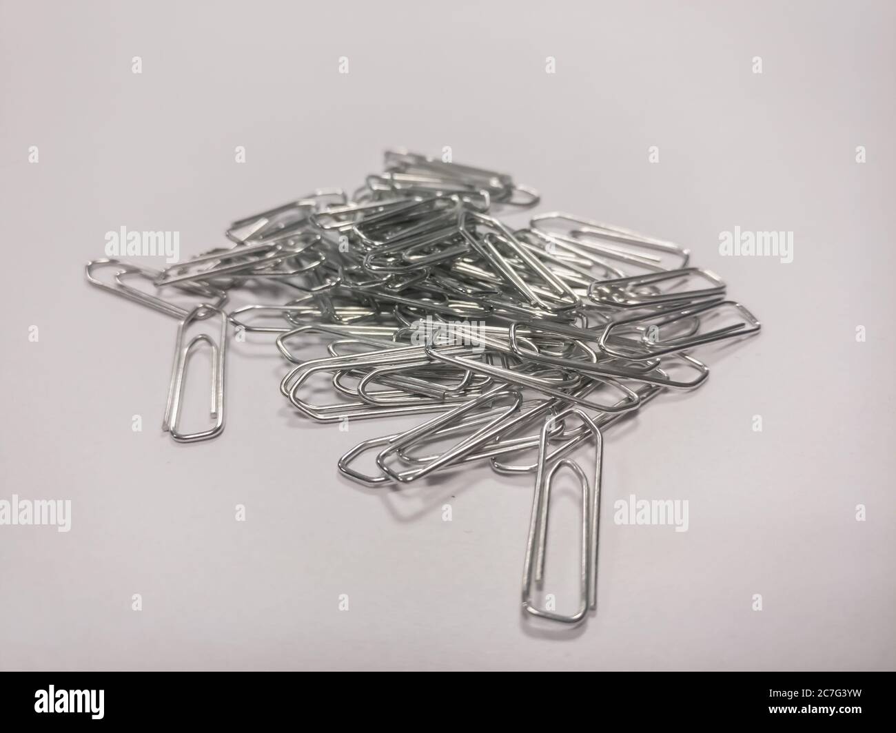 Pile of metal paper clips on a white background Stock Photo - Alamy