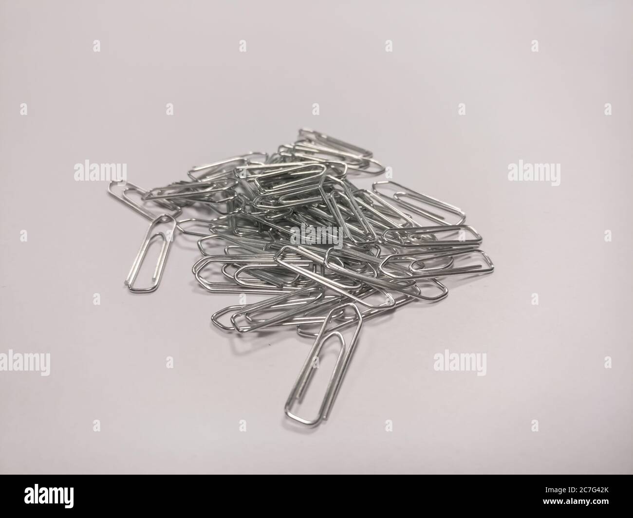 Pile of metal paper clips on a white background Stock Photo - Alamy