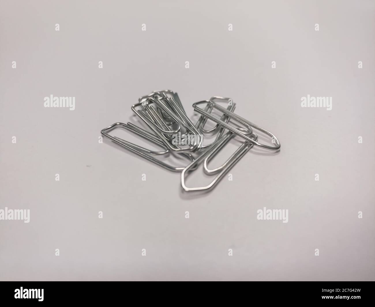 Pile of metal paper clips on a white background Stock Photo - Alamy