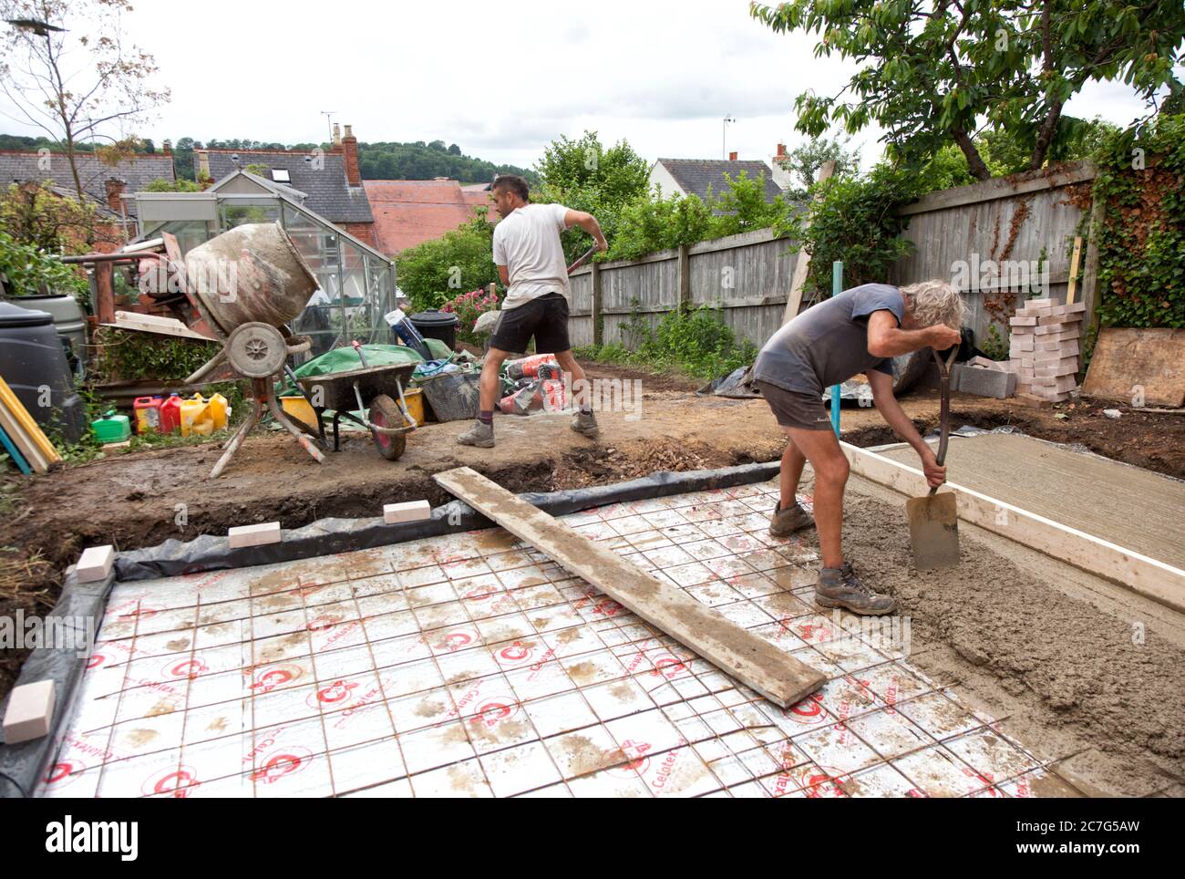 Two builders constructing a reinforced concrete base for a garden ...