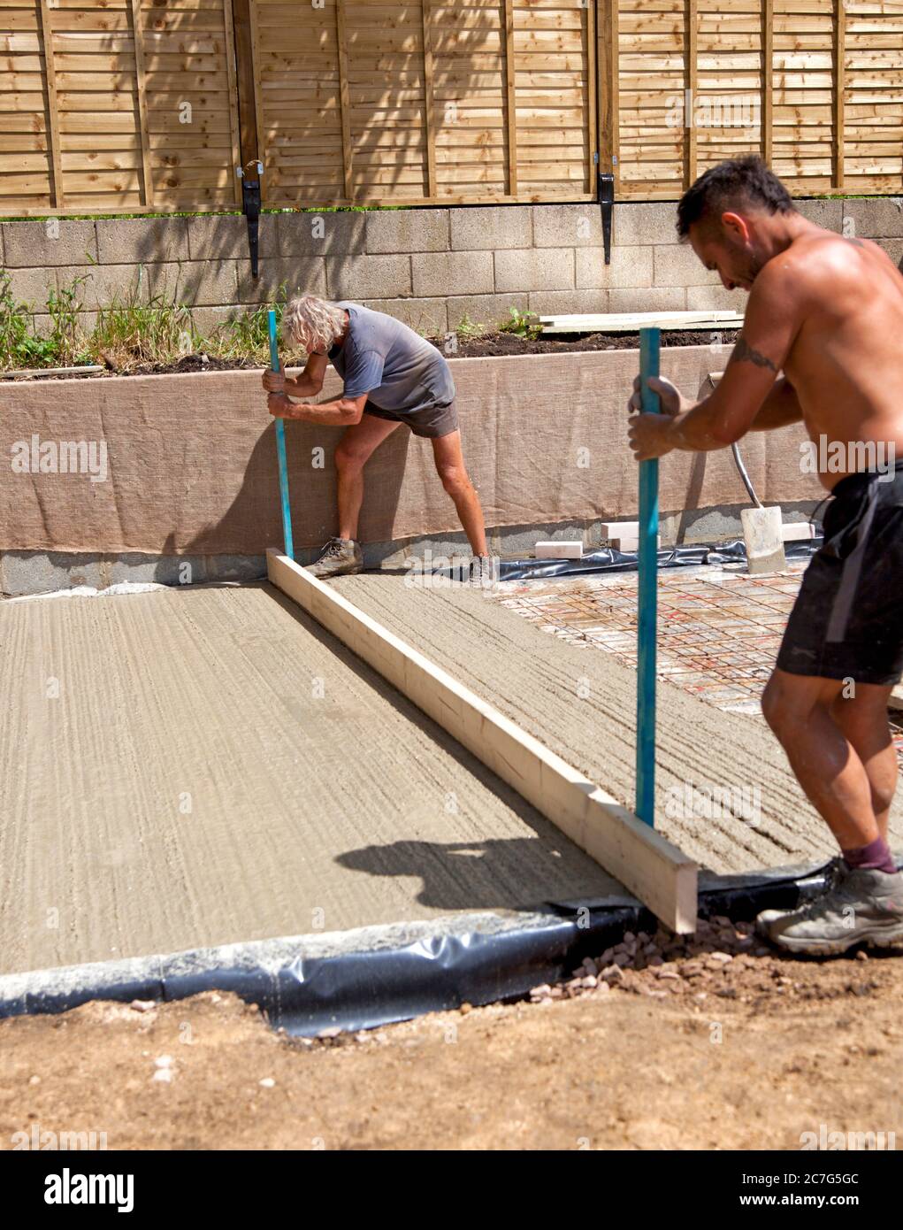 Two builders leveling a concrete base for a garden studio Stock Photo ...