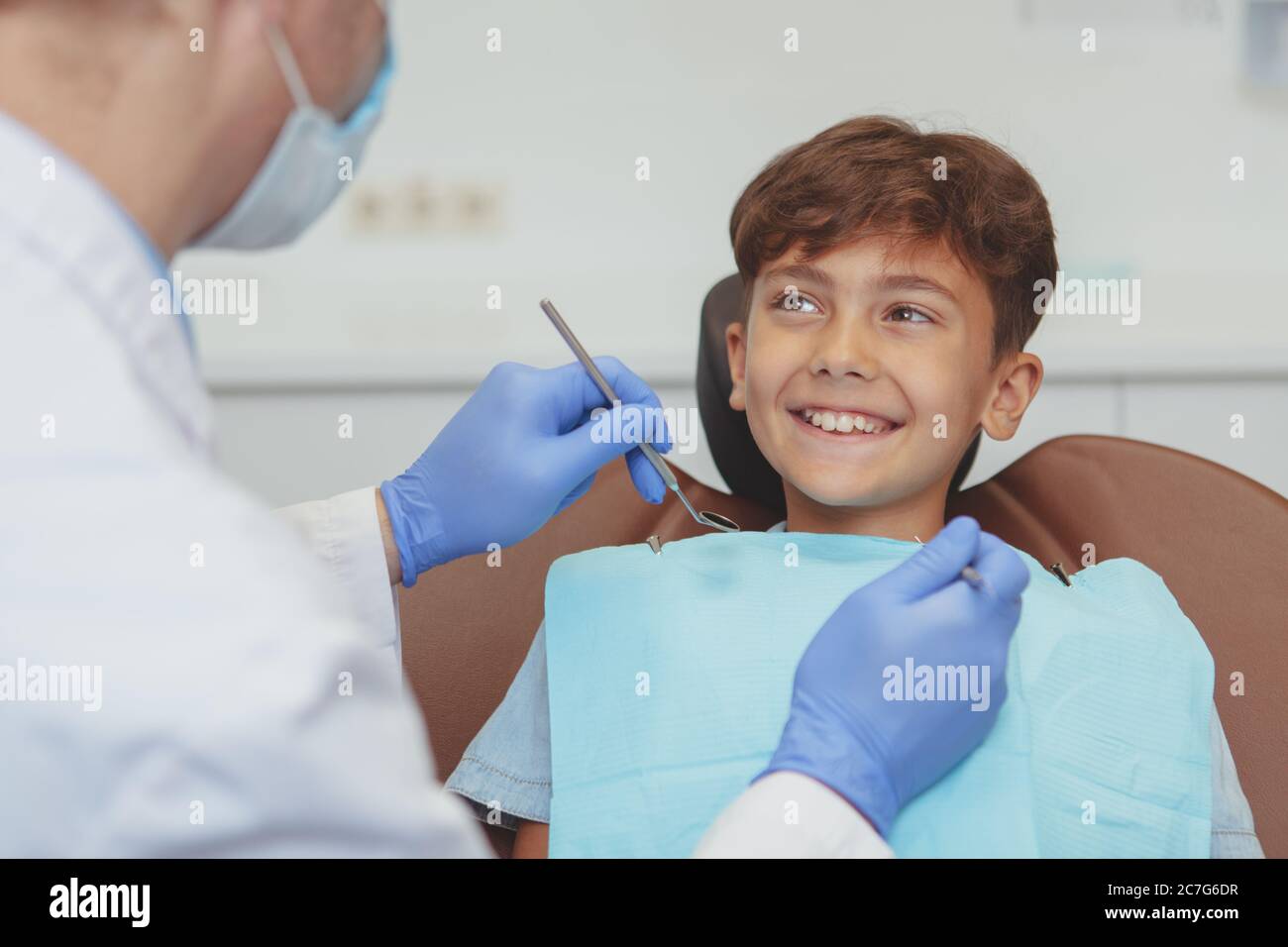 Adorable happy healthy boy smiling cheerfully at his dentist, sitting ...