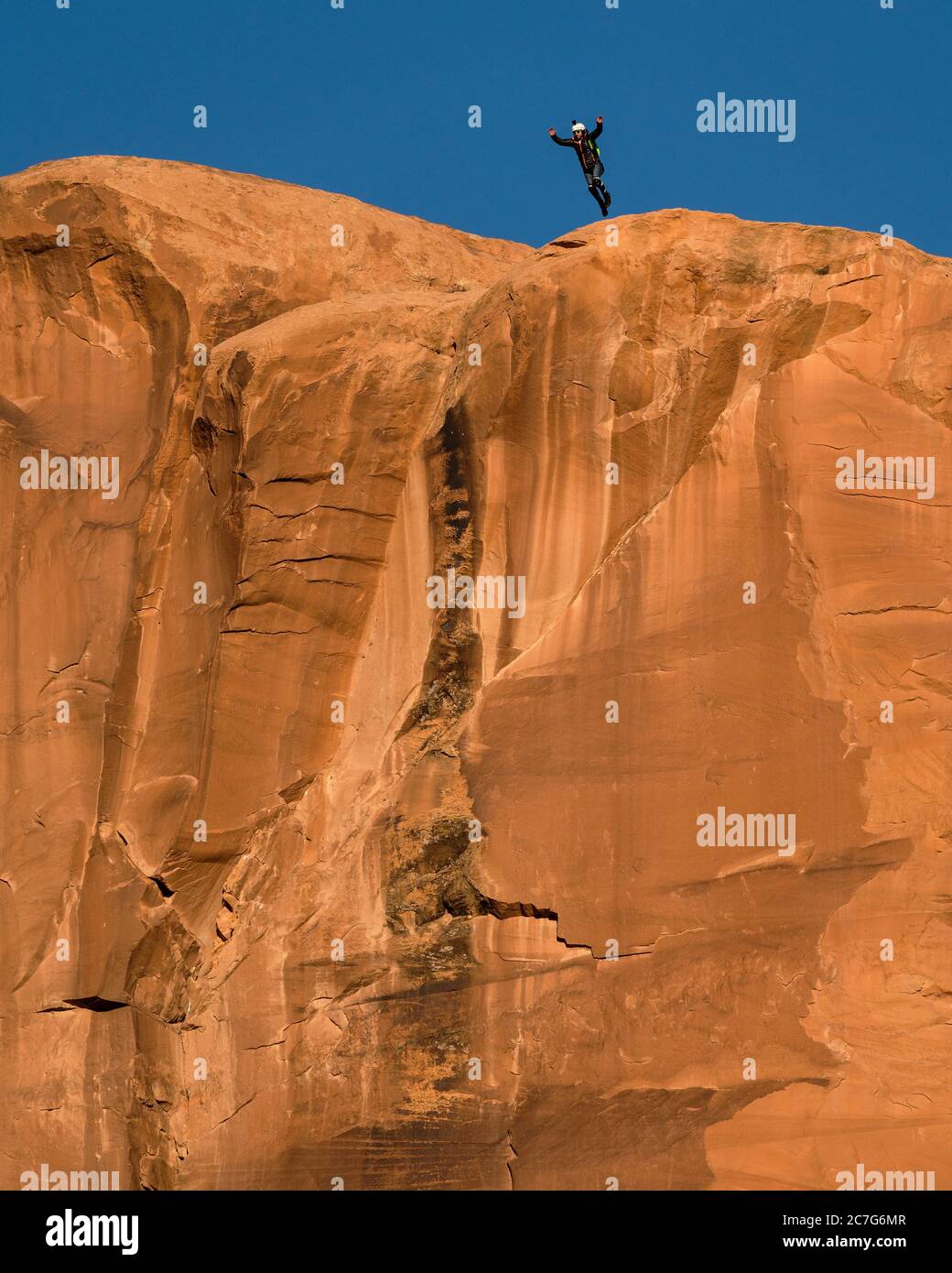 USA, Utah, Moab, A basejumper leaps off the top of the 400 foot ...