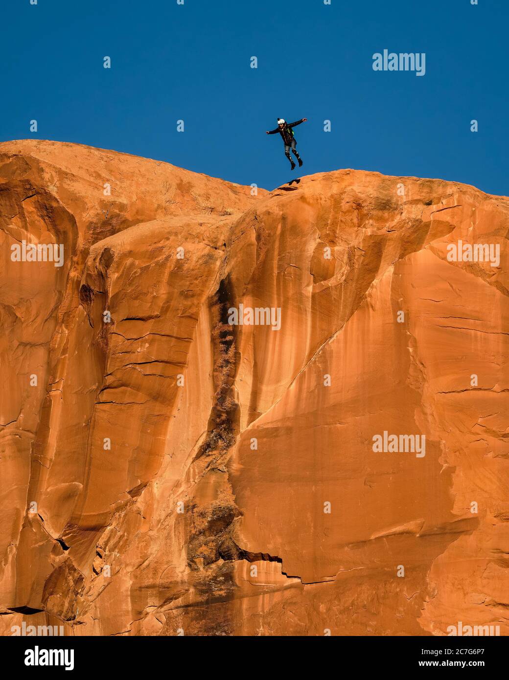 USA, Utah, Moab, A basejumper leaps off the top of the 400 foot ...