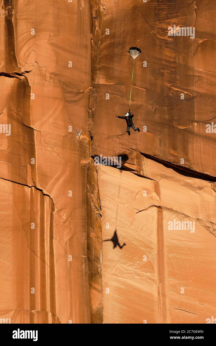 USA, Utah, Moab, A base jumper leaps off the 400 foot vertical face of ...