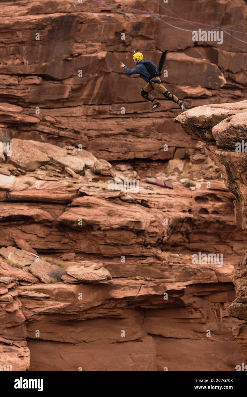 USA, Utah, Moab, A base Jumper leaps off the clifftop 950 feet above ...