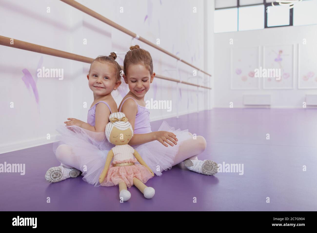 Two charming little ballerinas sitting back to back on the floor at ...